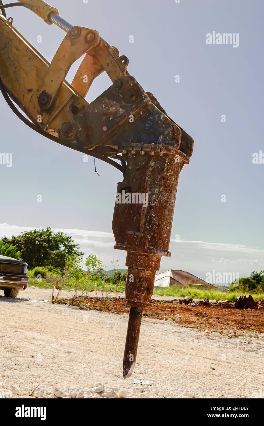 A heavy duty jackhammer attached to the arm of a frontend loader is ...