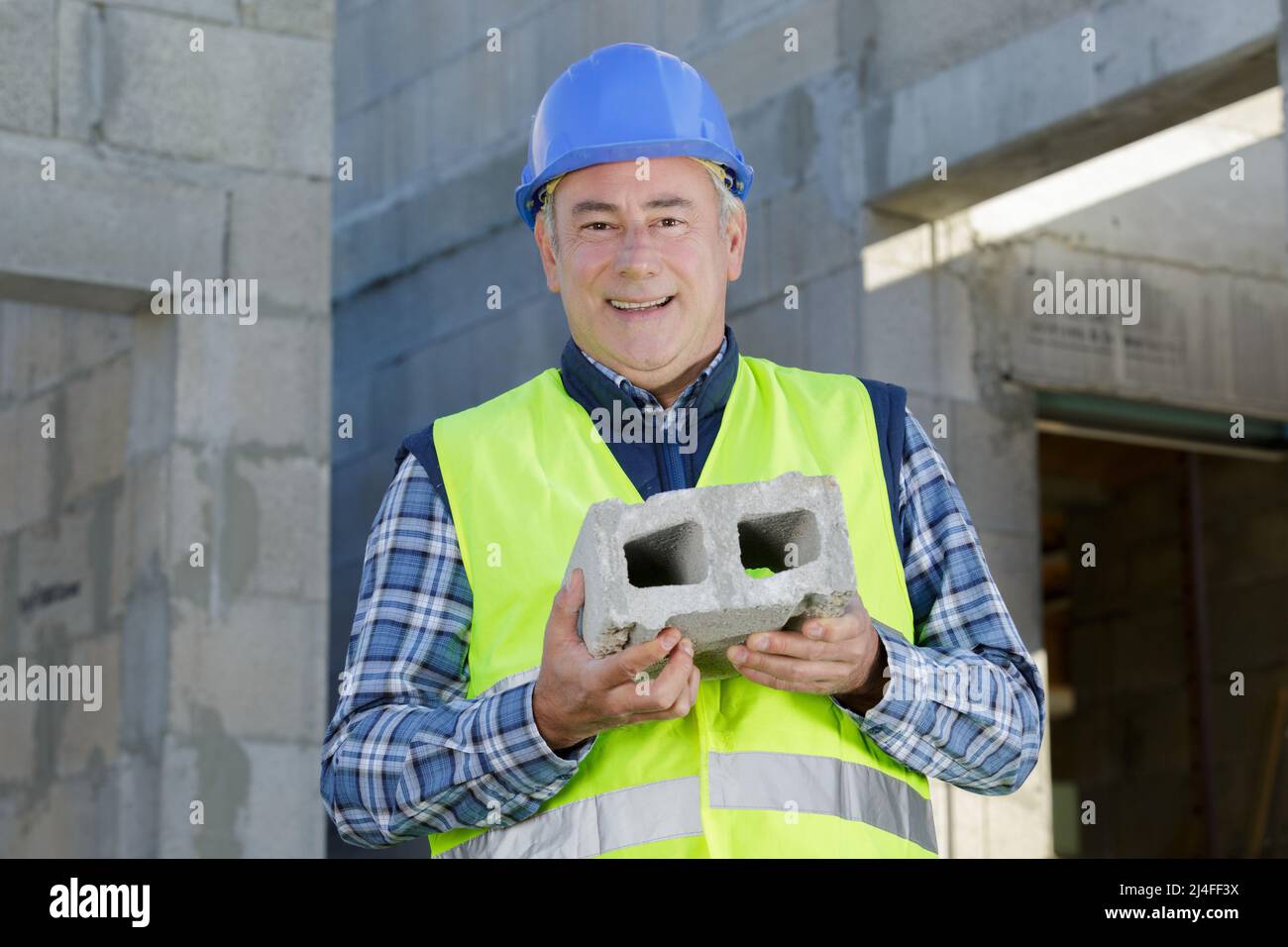 builder man holding concrete blocks for house building Stock Photo - Alamy