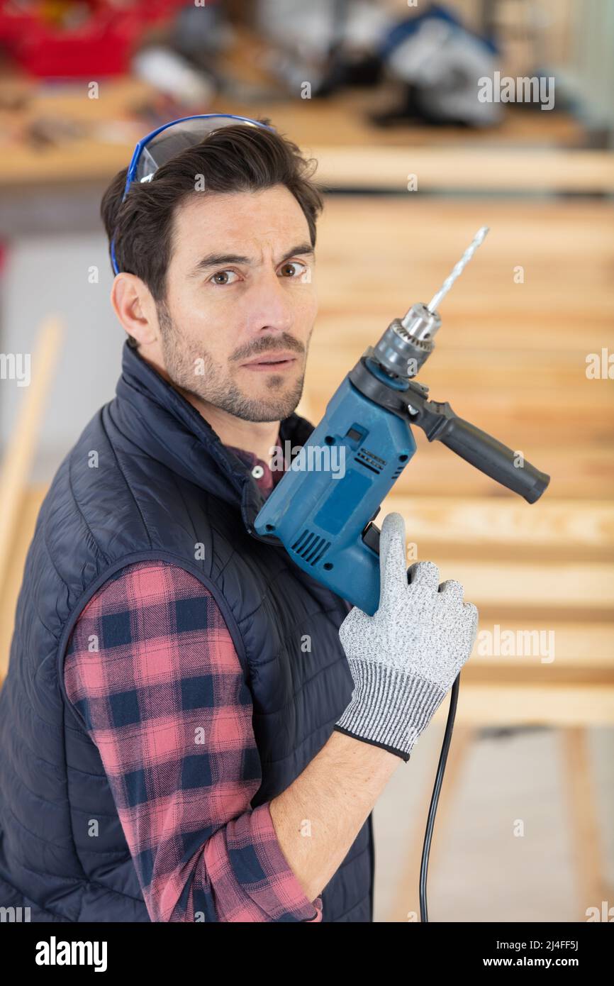 portrait of a serious contractor holding a drill Stock Photo - Alamy