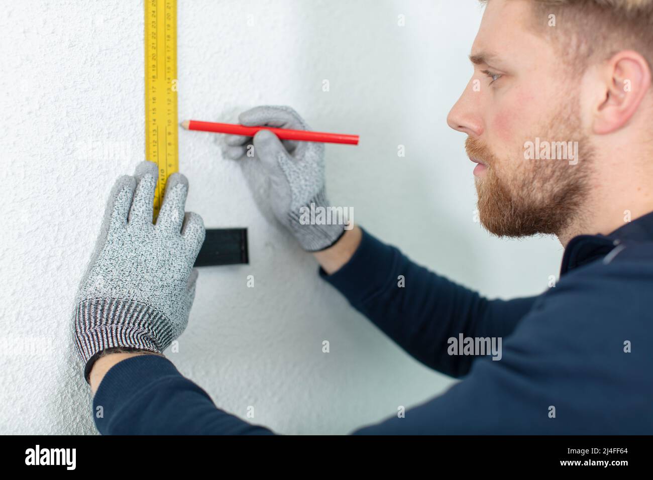 builder marking off a measurement on a new interior wall Stock Photo ...