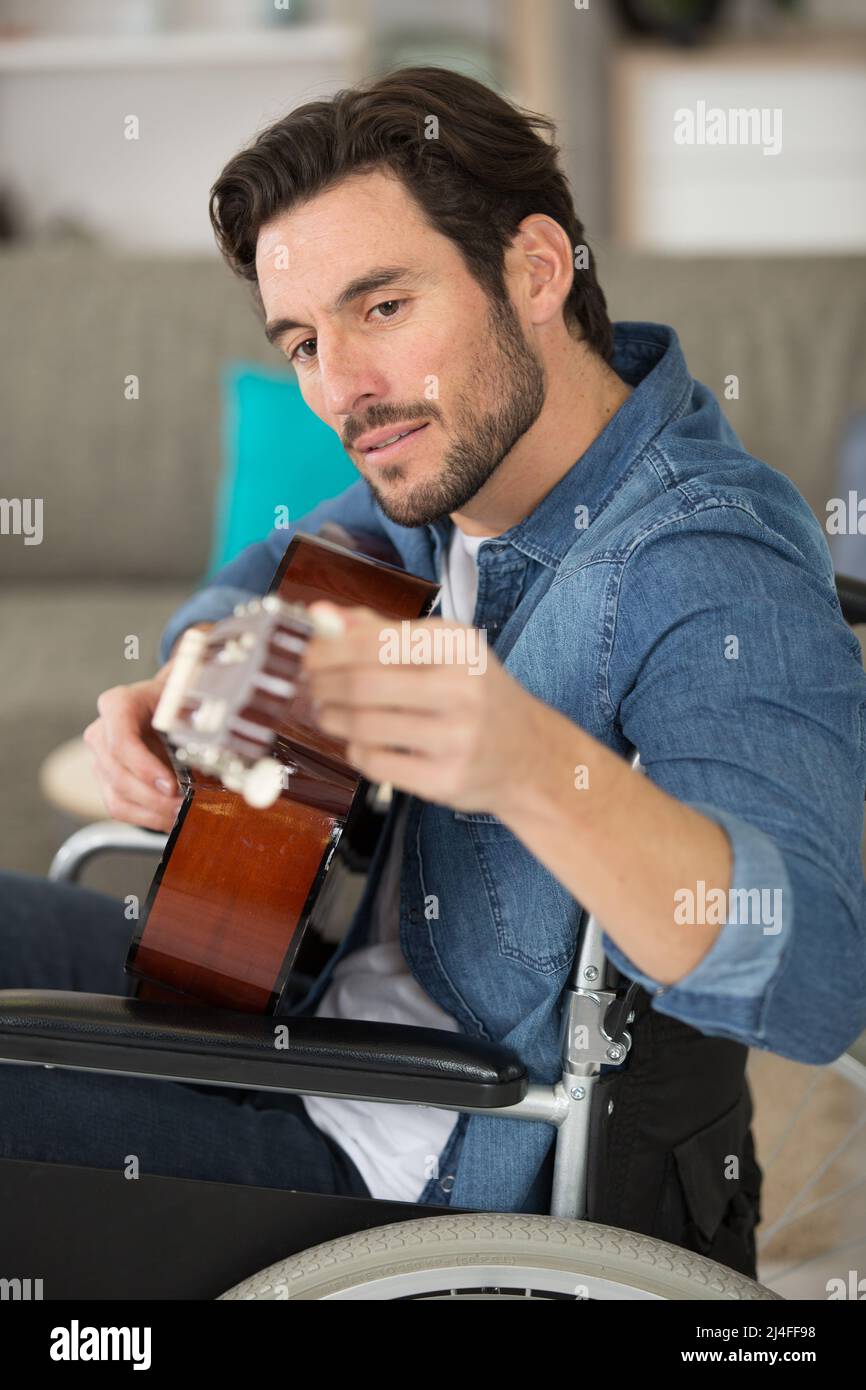man in wheelchair tuning his guitar Stock Photo - Alamy