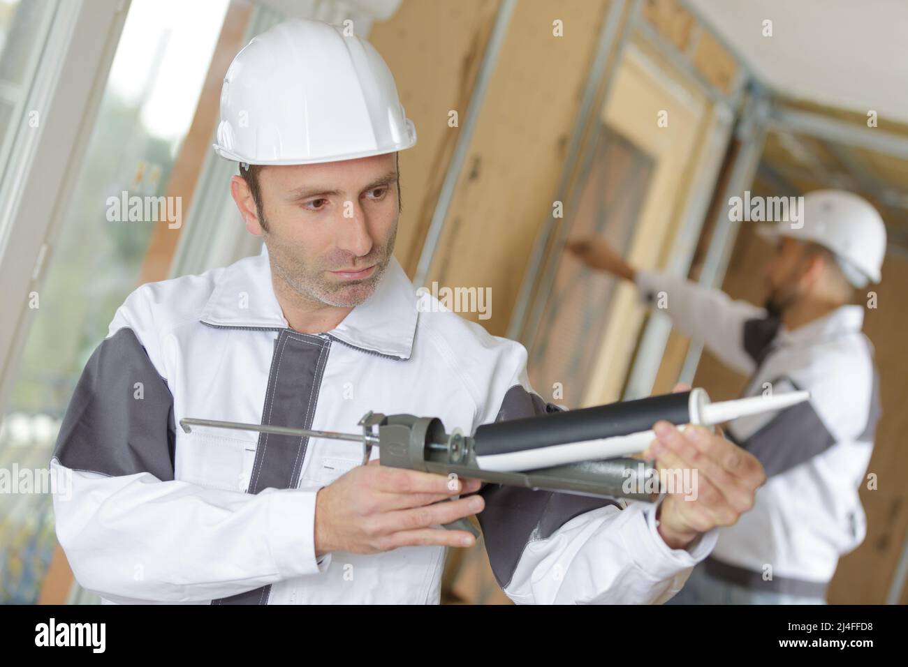 portrait of workers using a silicone gun Stock Photo - Alamy