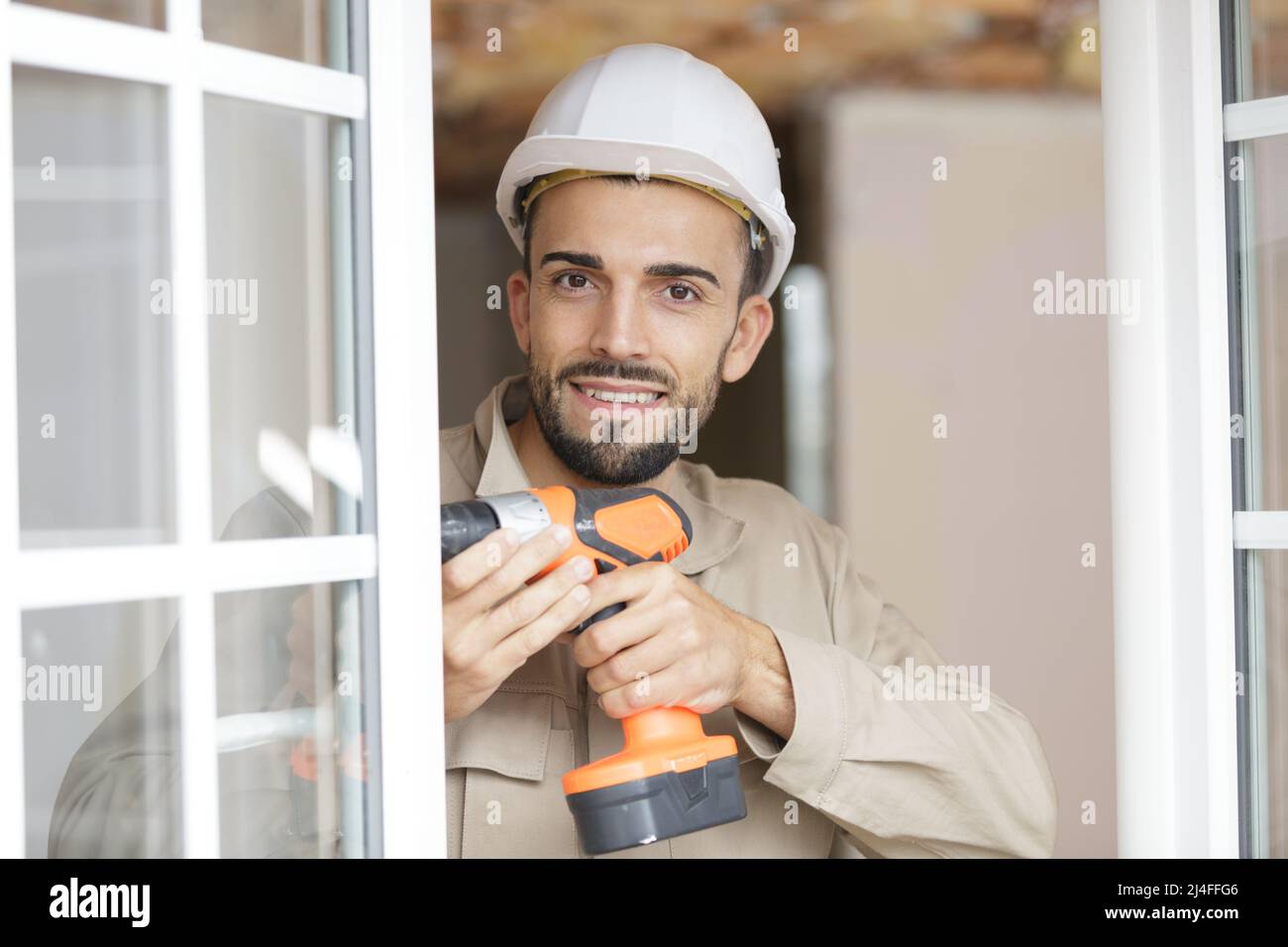 man drilling a hole in a window frame Stock Photo - Alamy