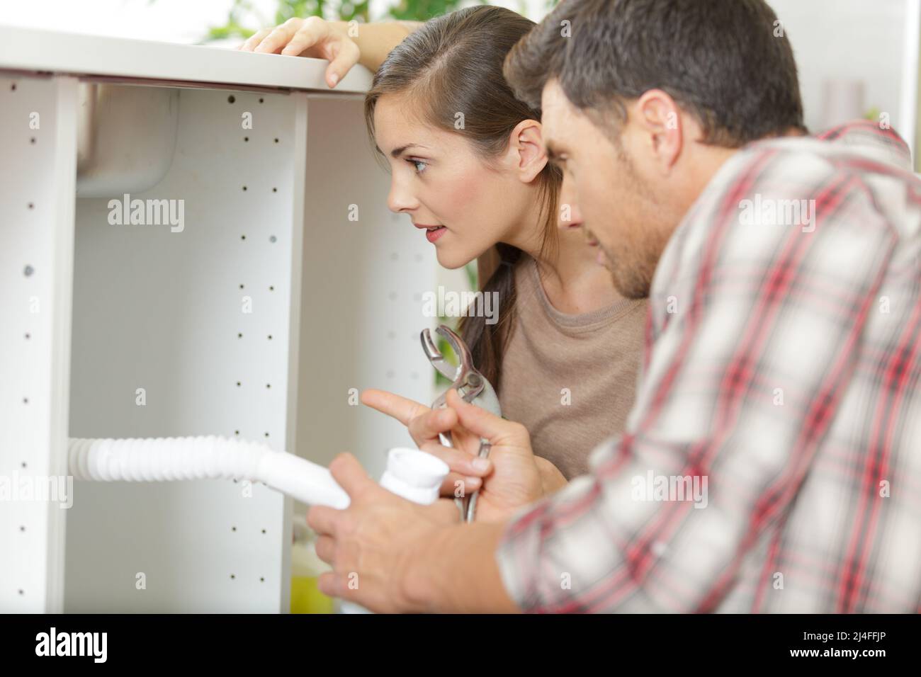 male plumber repairing sink and talking to client Stock Photo - Alamy