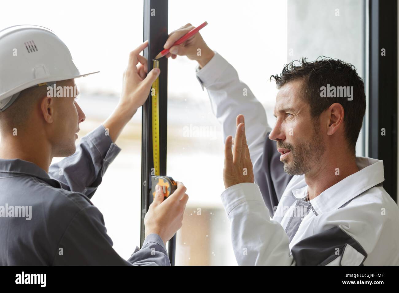service men installing windows with measure tape Stock Photo - Alamy