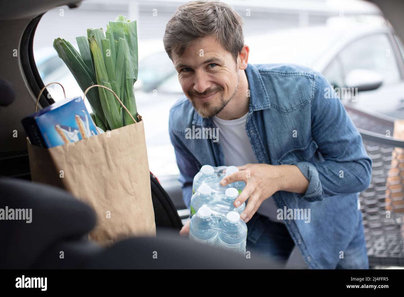 man placing shopping bags in the boot of his car Stock Photo - Alamy
