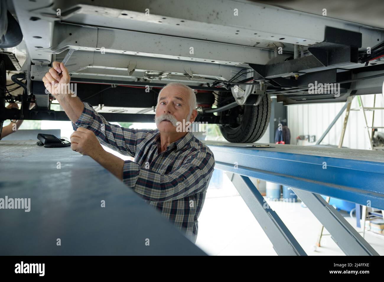 senior mechanic working under a car in the garage Stock Photo - Alamy