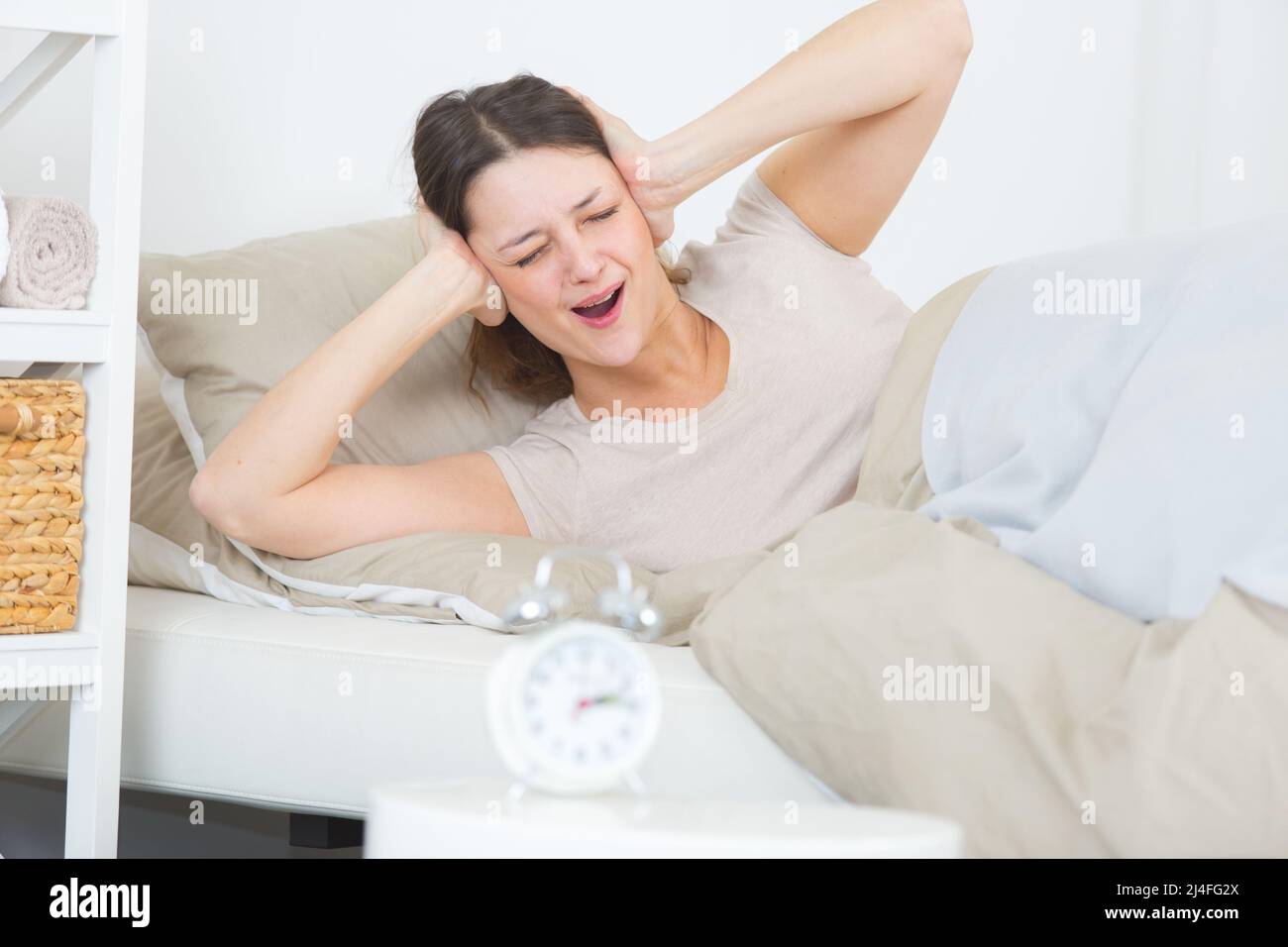 woman covering her ears on bed Stock Photo - Alamy