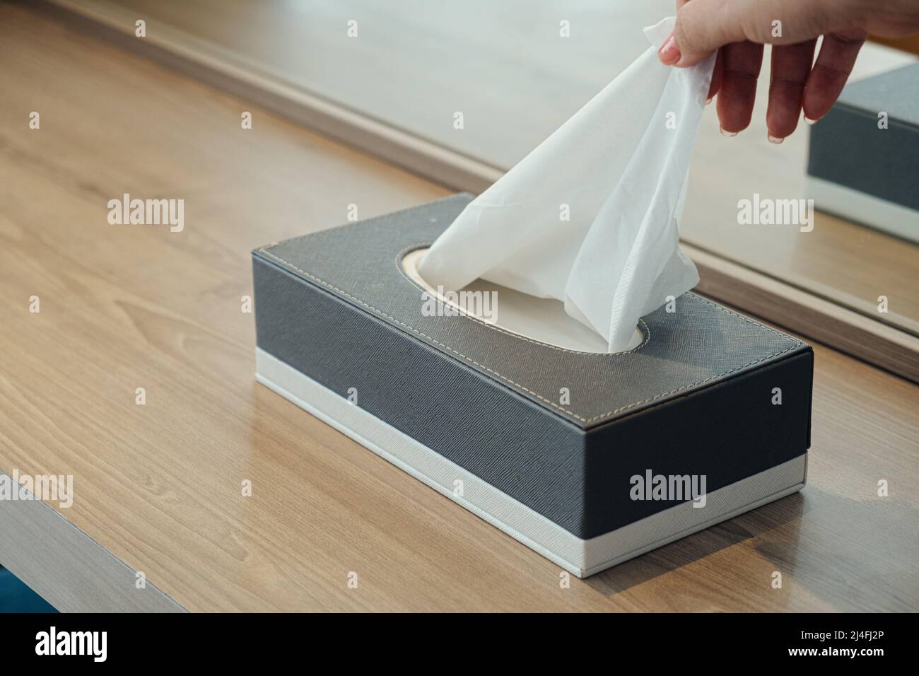Closeup woman hand picking white tissue paper from tissue box on wooden ...