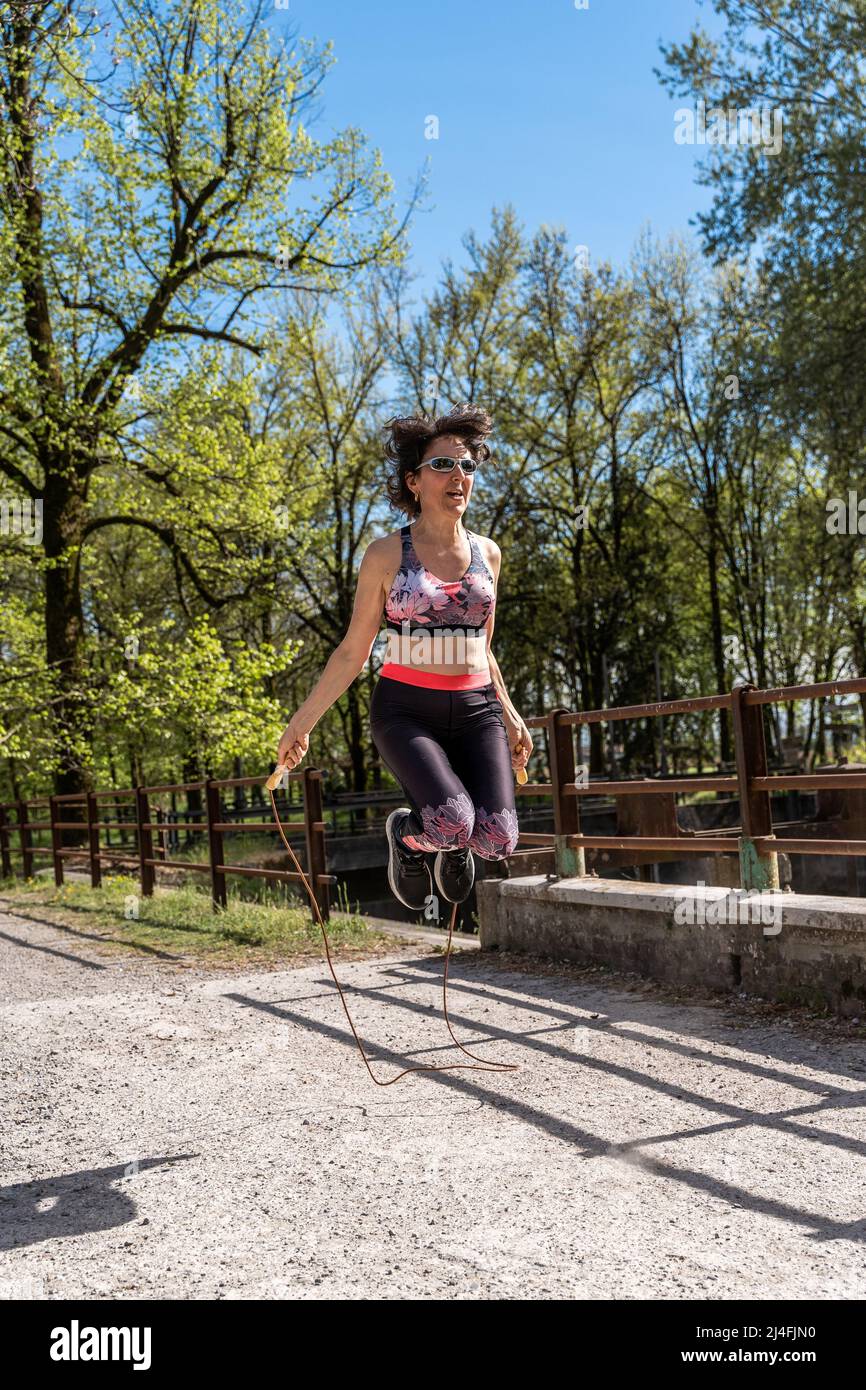 beautiful middle aged woman jumping rope outdoors - healthy lifestyle ...
