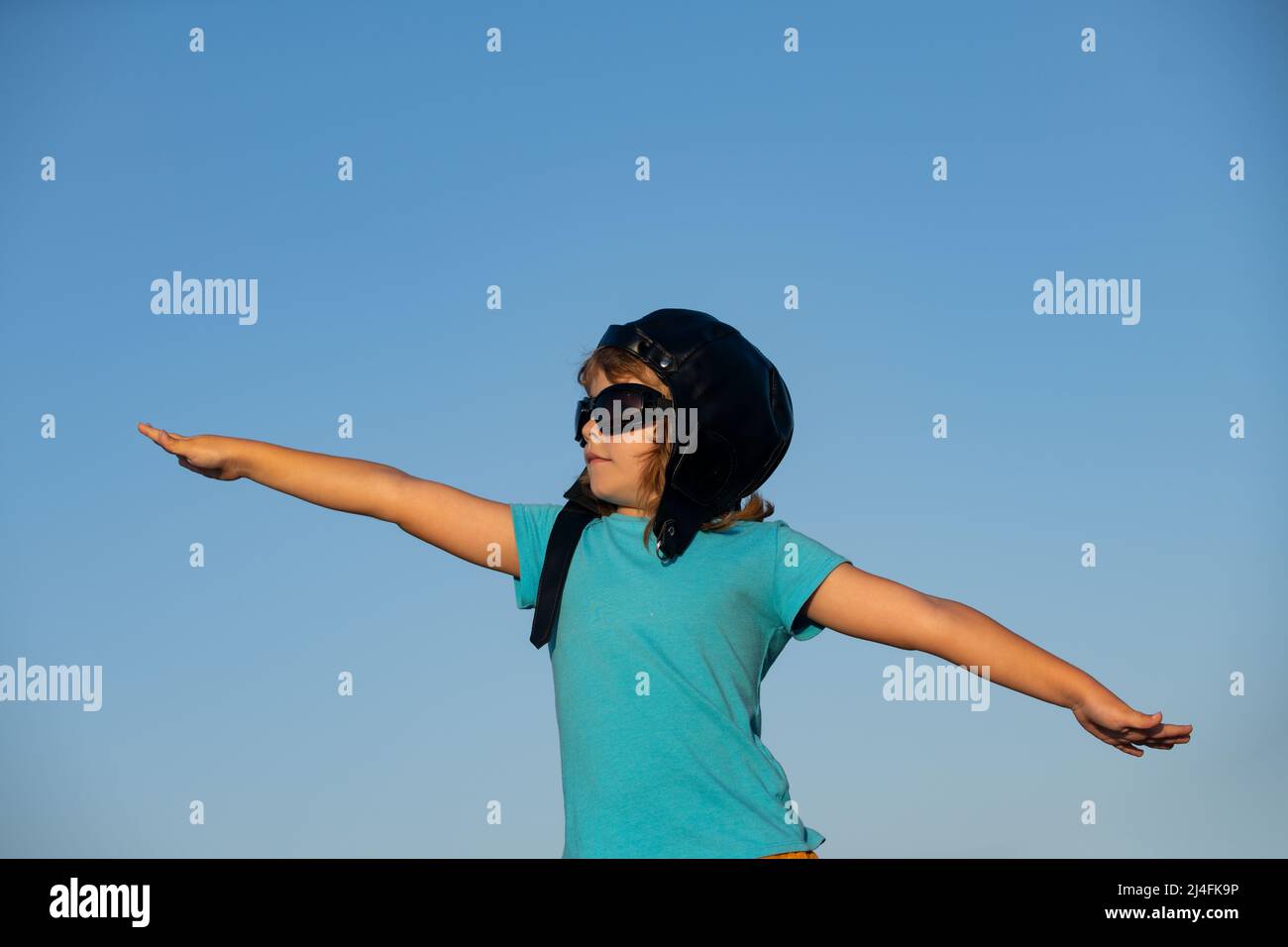 Kid with pilot goggles and helmet dreaming and plays with a toy plane ...