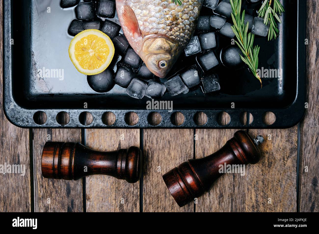 Cooking fish, raw fish on a baking sheet with ice cubes, lemon slices ...