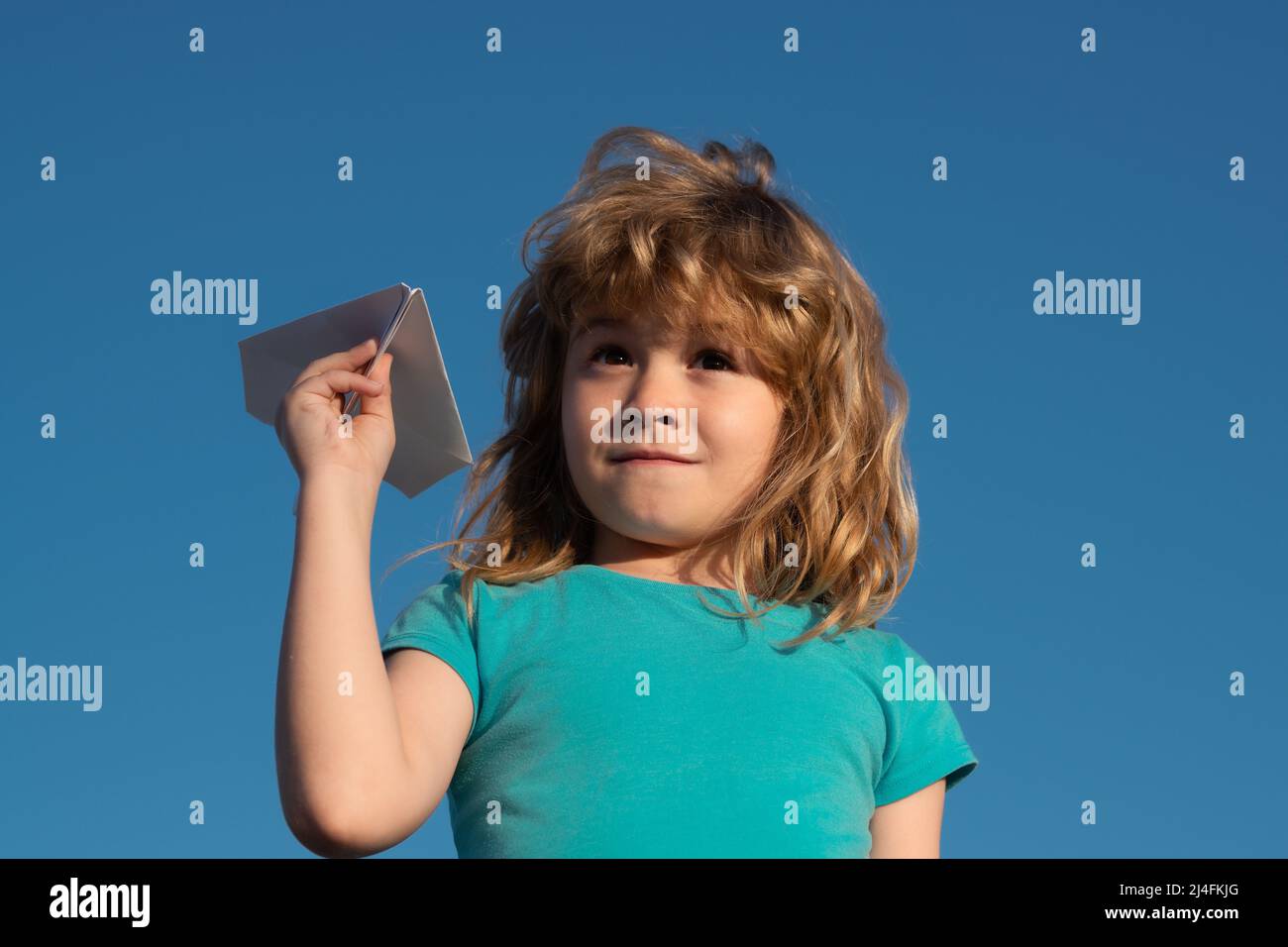 Fun little boy dreams of aviator while playing a paper plane at sky ...