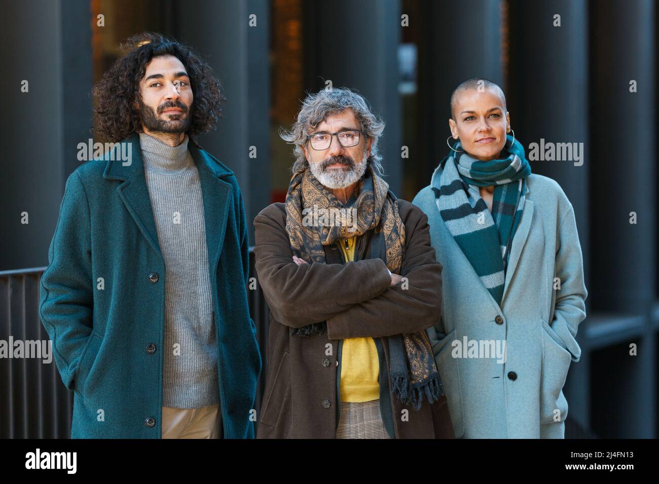 Three professional business people posing together outdoors on the ...