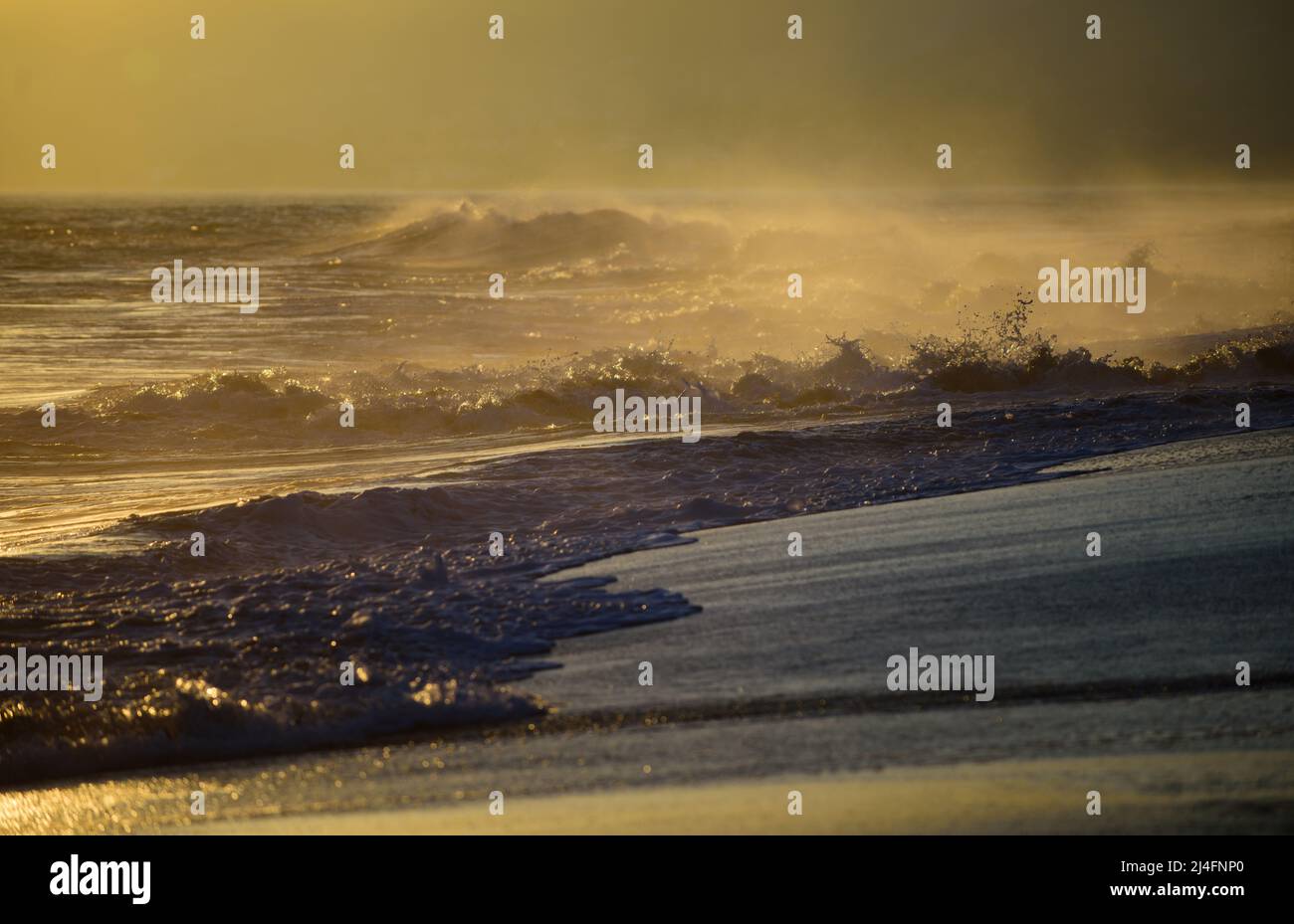 Sunset with large yellow sun under the sea surface. Waves splashes ...