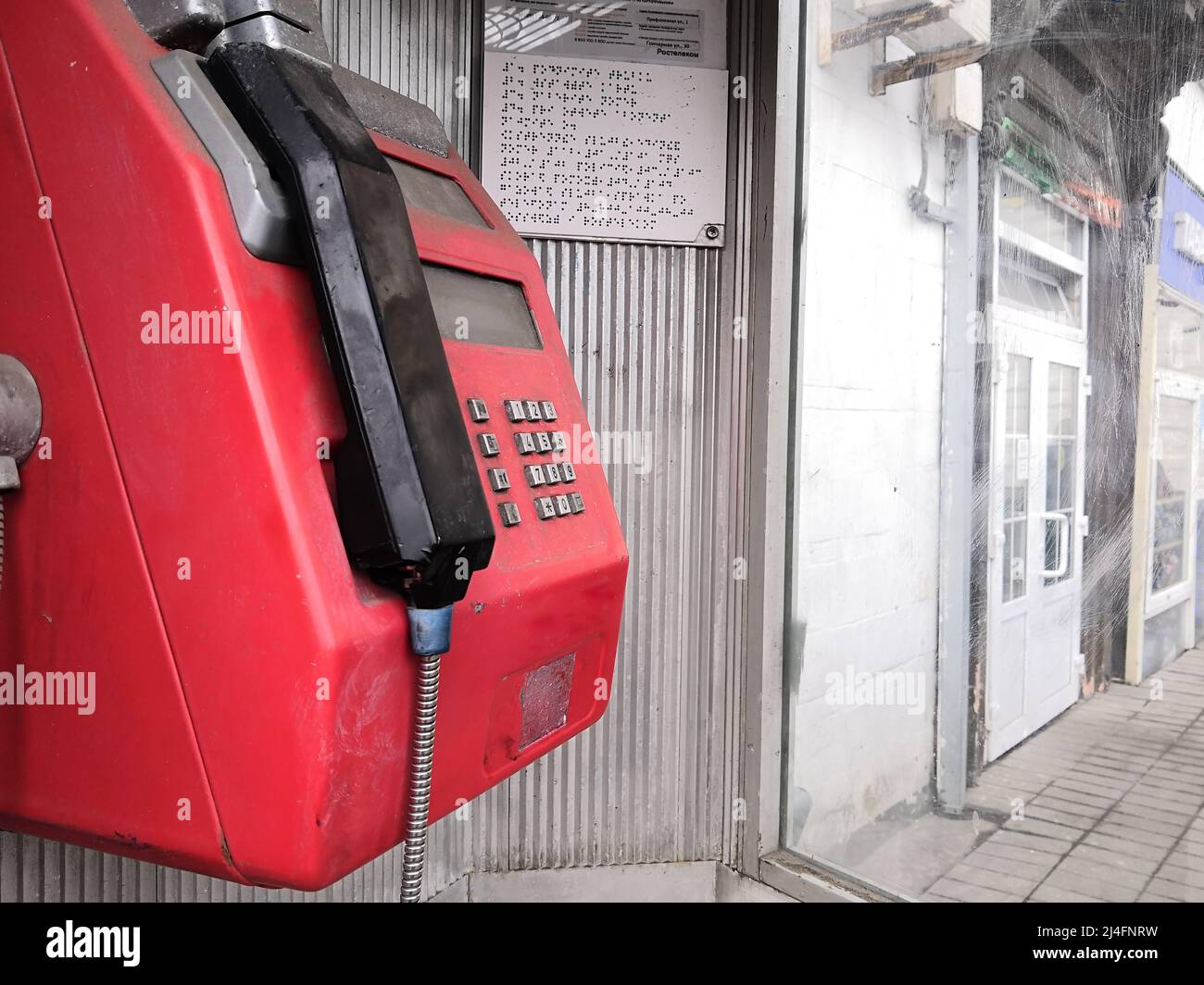 Old red scratched dirty telephone set in a public telephone box on the ...