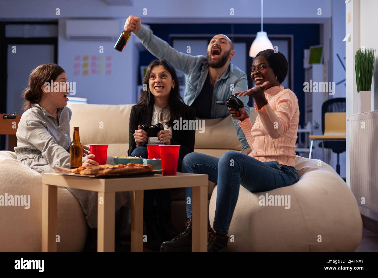 Happy workmates celebrating video games win with drinks in business ...