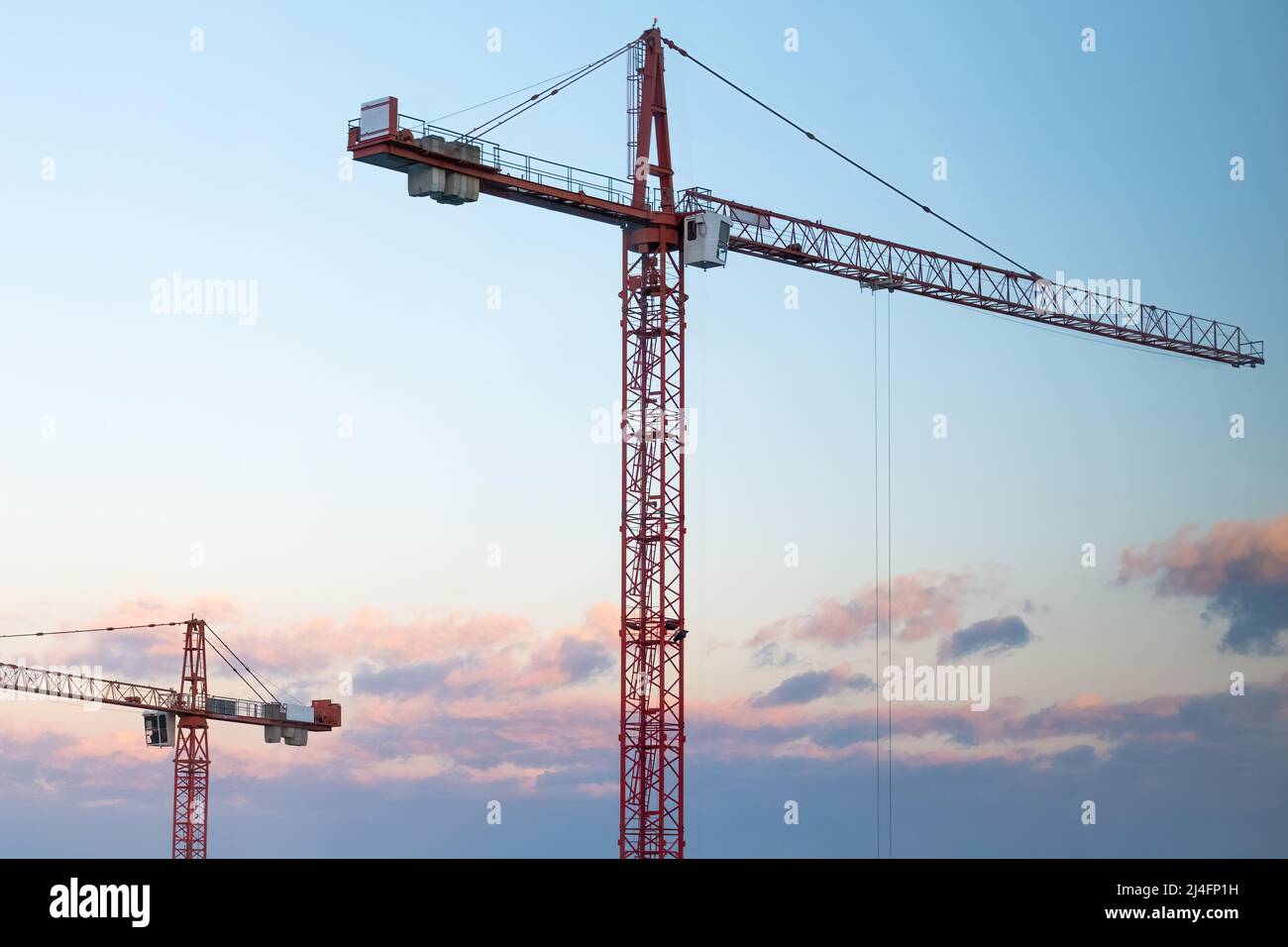 Tall tower cranes on the construction against sunset Stock Photo - Alamy