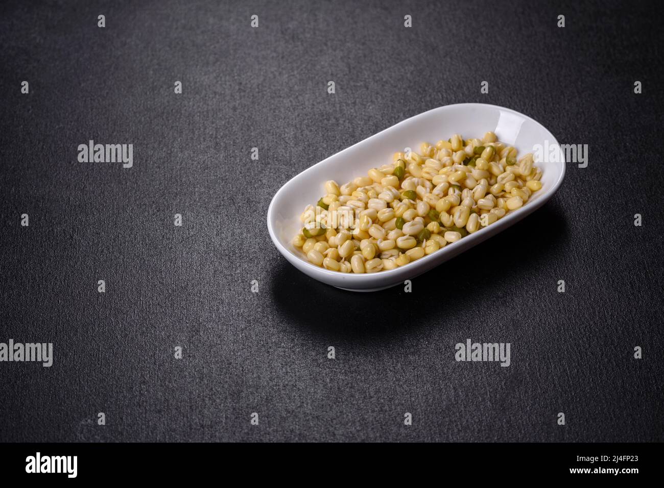 Green mung beans in a bowl on a dark concrete table. Legume plant for a ...