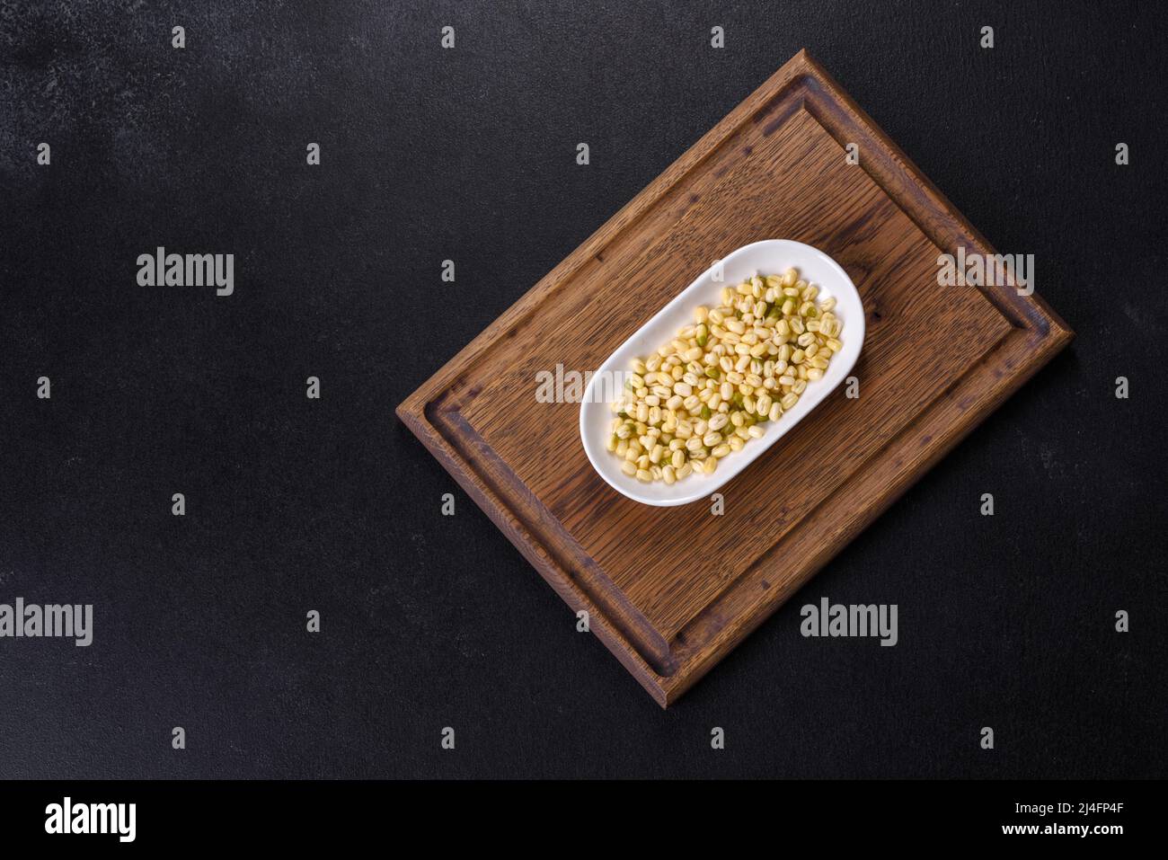 Green mung beans in a bowl on a dark concrete table. Legume plant for a ...