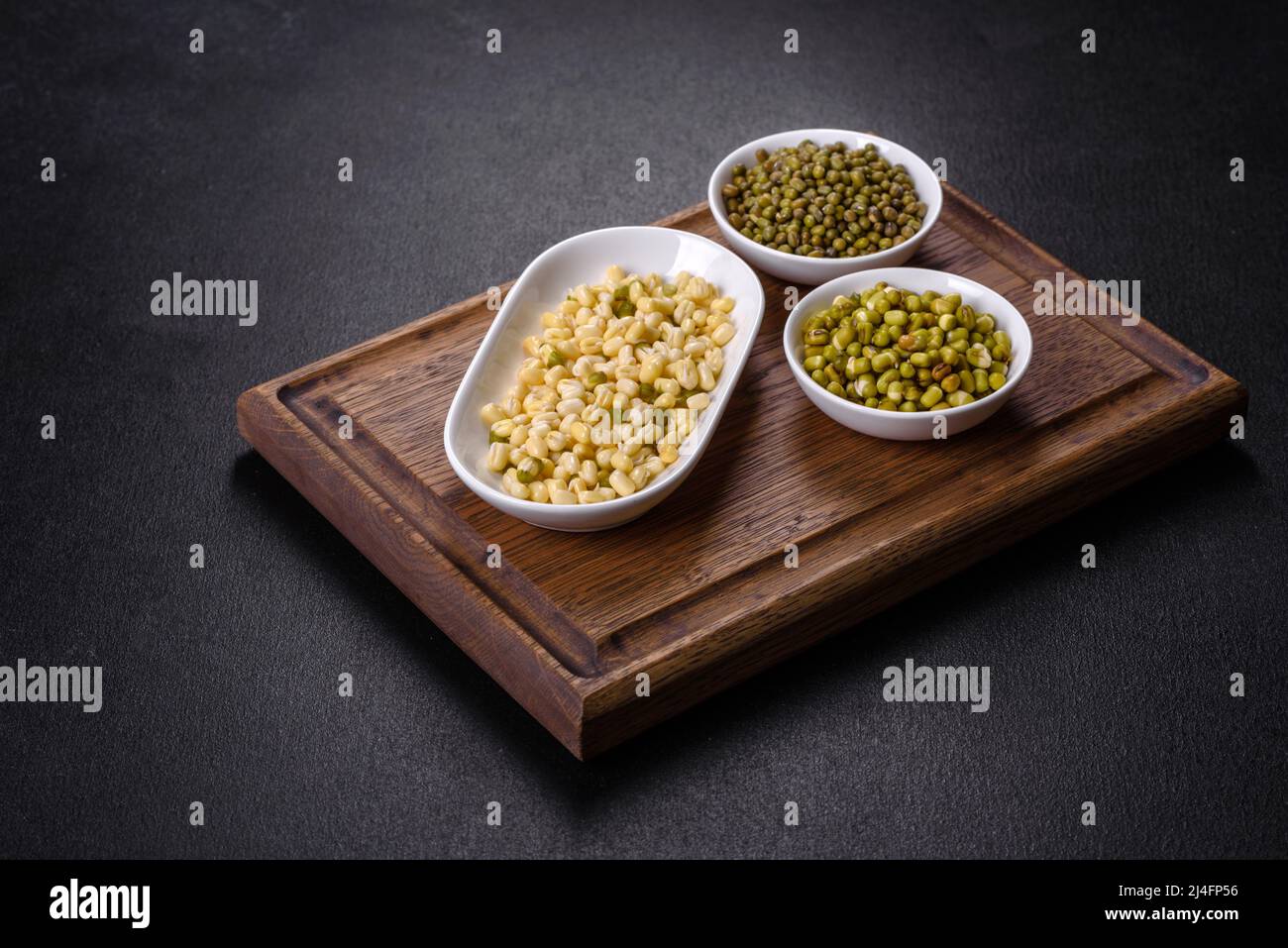 Green mung beans in a bowl on a dark concrete table. Legume plant for a ...