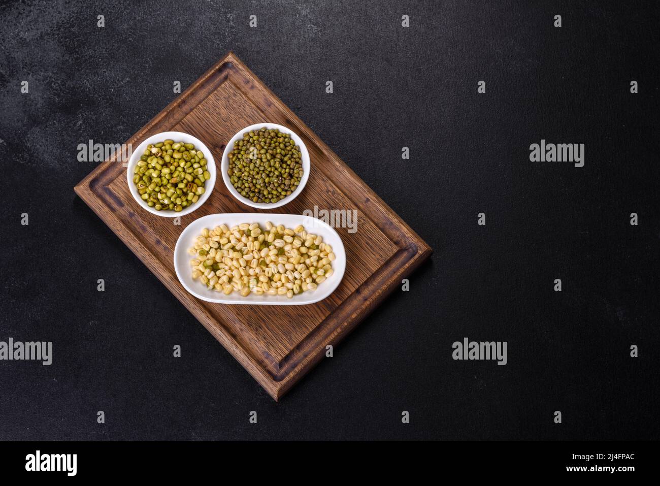 Green mung beans in a bowl on a dark concrete table. Legume plant for a ...