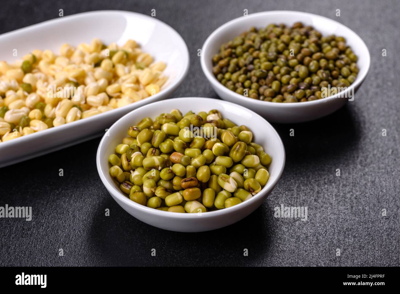 Green mung beans in a bowl on a dark concrete table. Legume plant for a ...