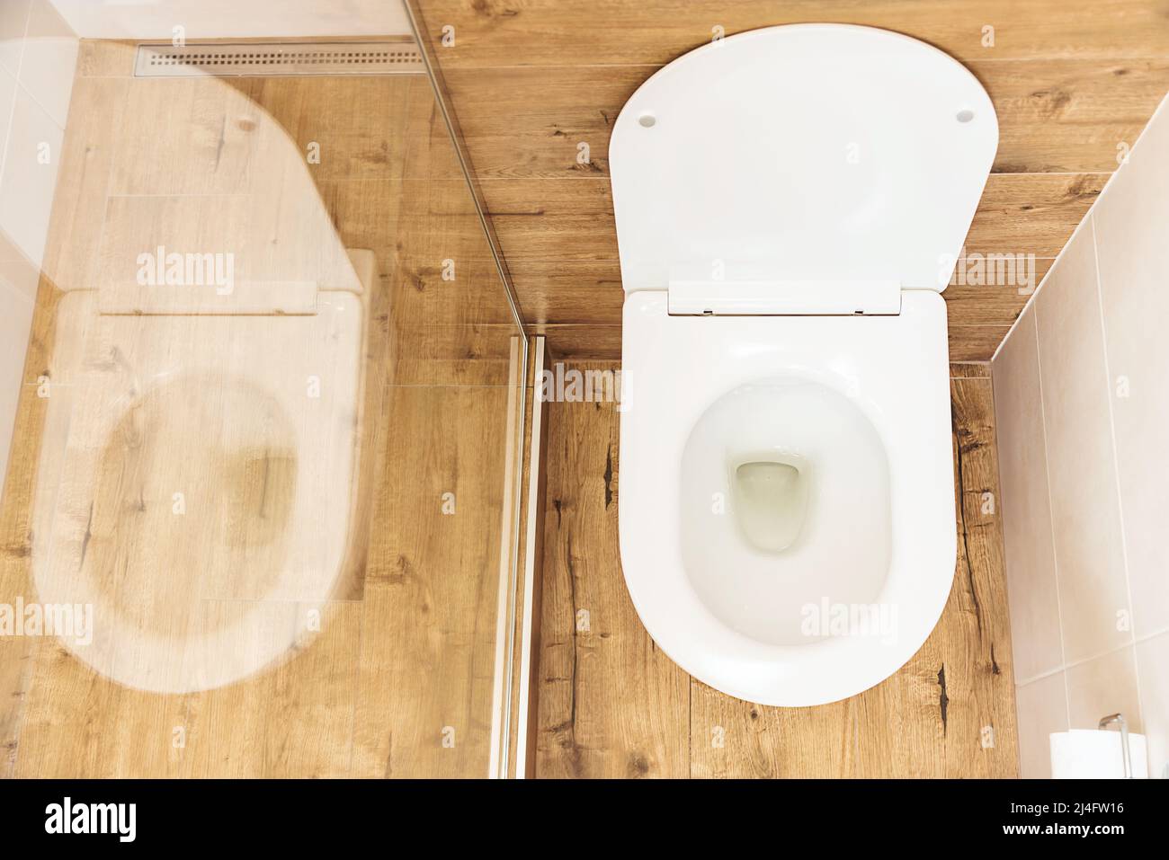 top view, clean white toilet bowl with open lid in modern bathroom ...