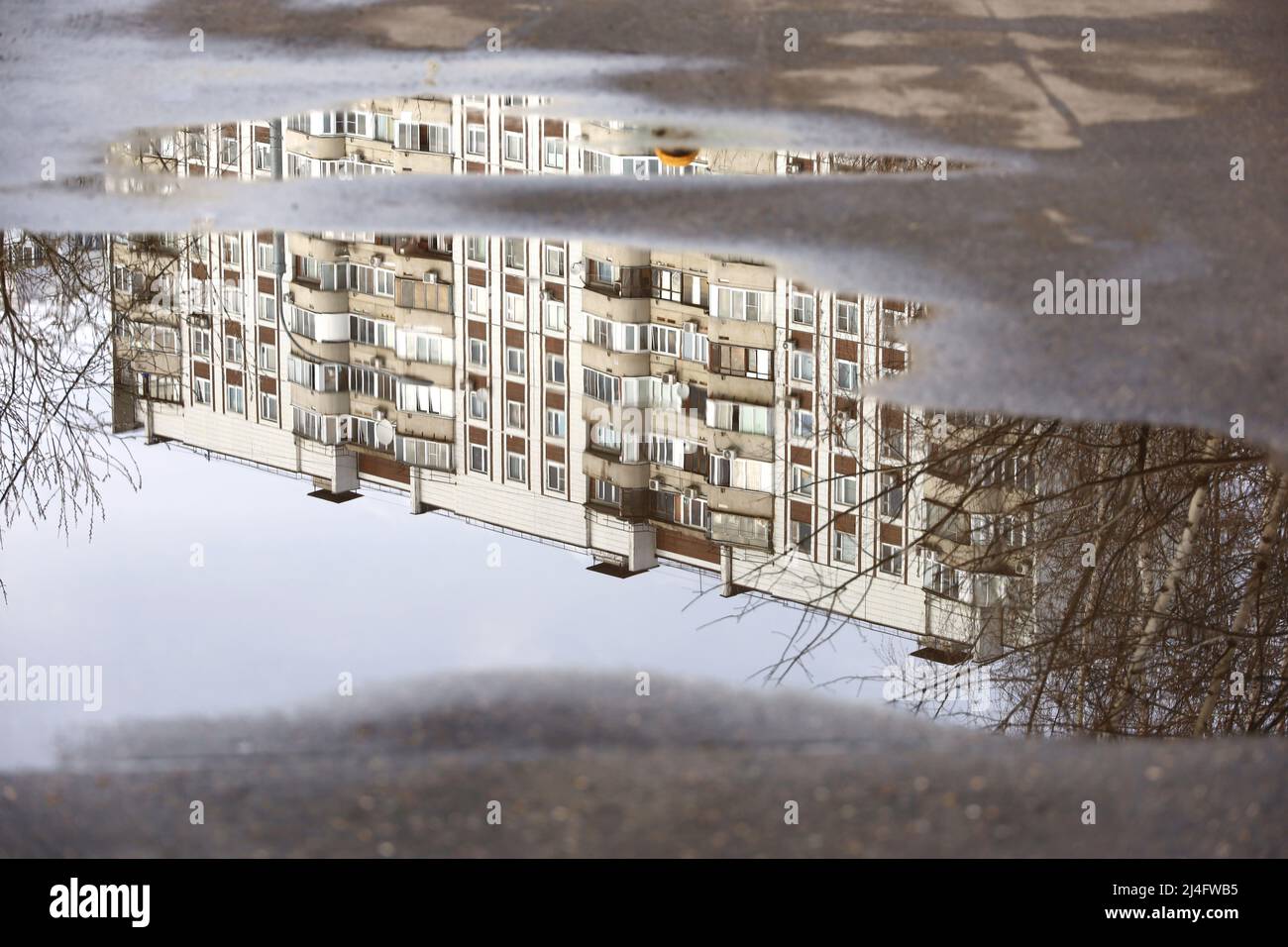 Puddle after rain with reflection of residential building in water ...