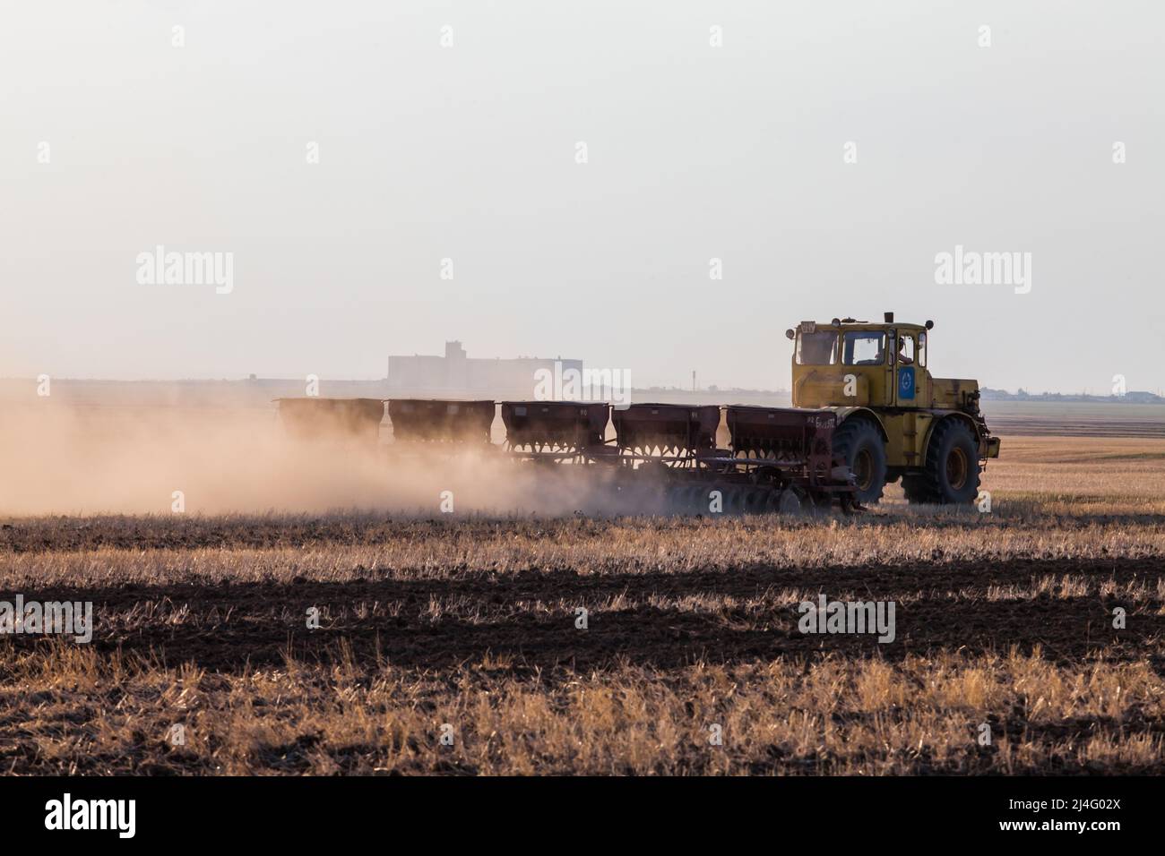 Tractor seeds wheat in field. Spring sowing season. Soviet elevator on ...