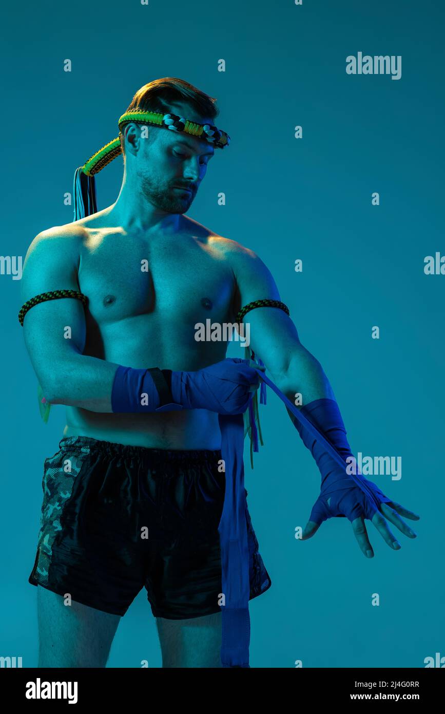 Half-length portrait of muscled man, thai boxer in sports uniform ...
