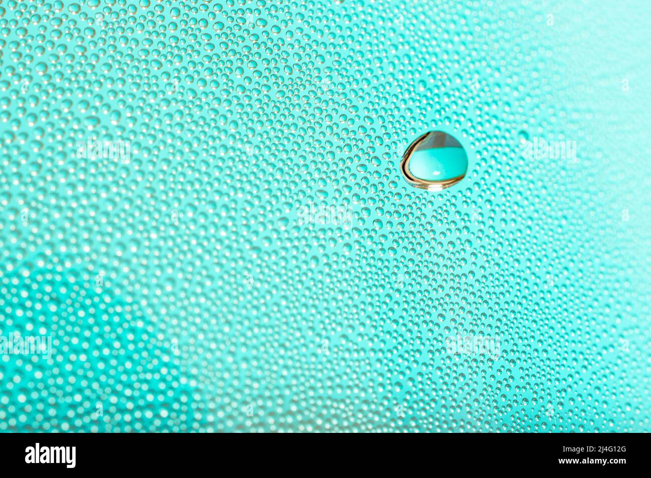 Big and small water droplets on vibrant turquoise background. The large ...