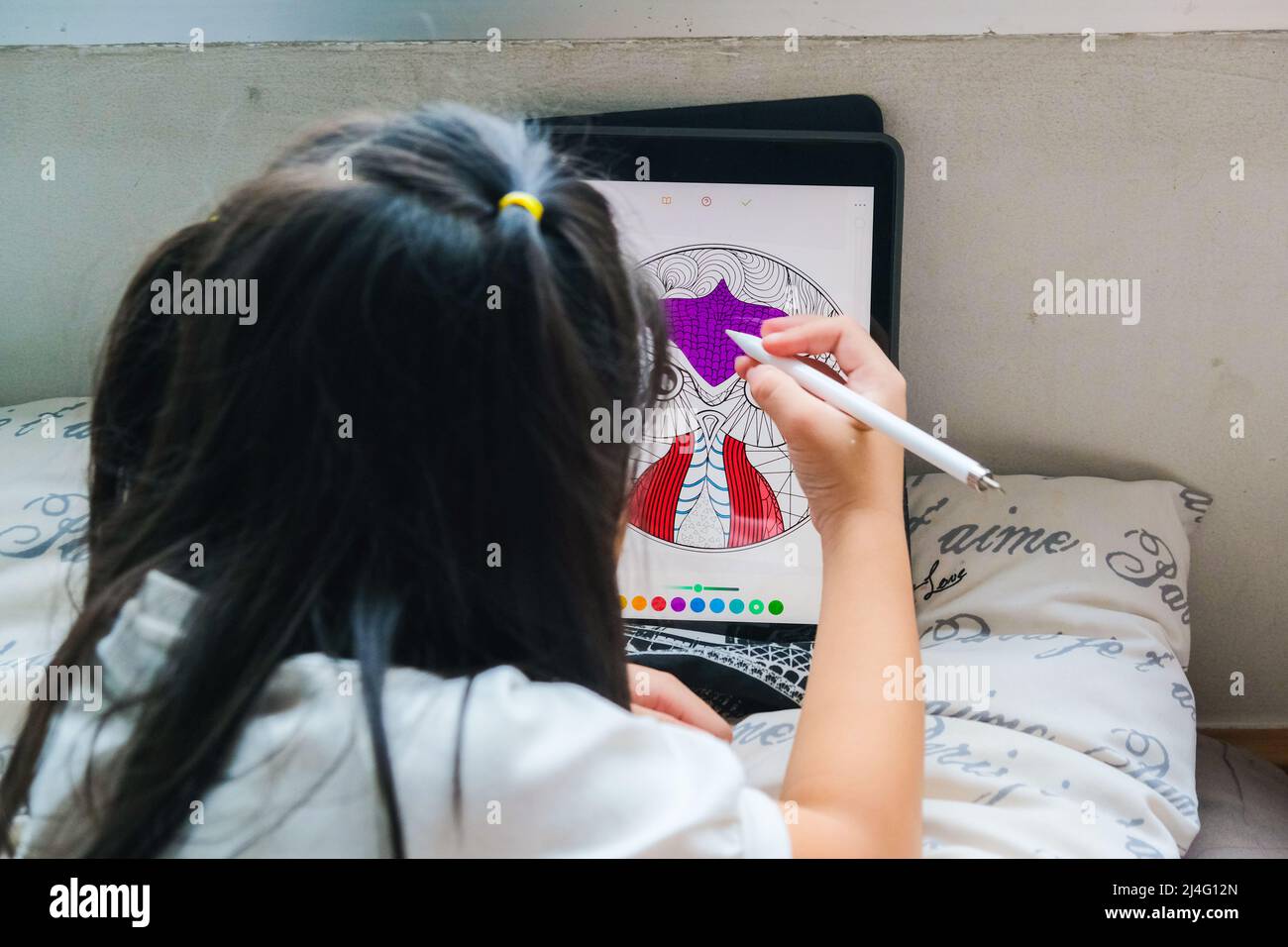 Little kid girl intend to drawing cartoon with tablet lying on bed art ...