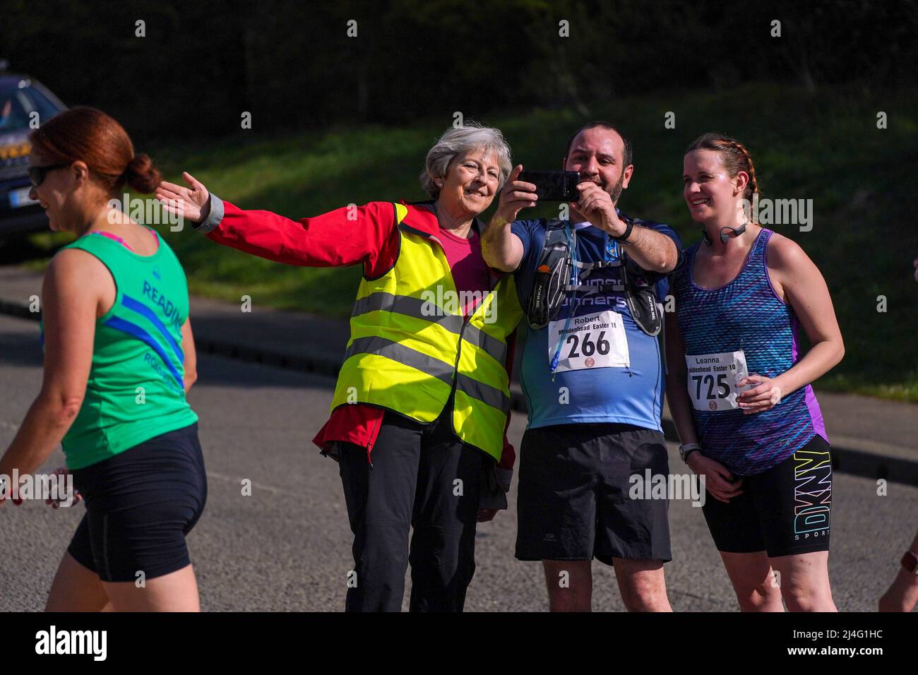 Former prime minister Theresa May poses for photographs with runners as ...