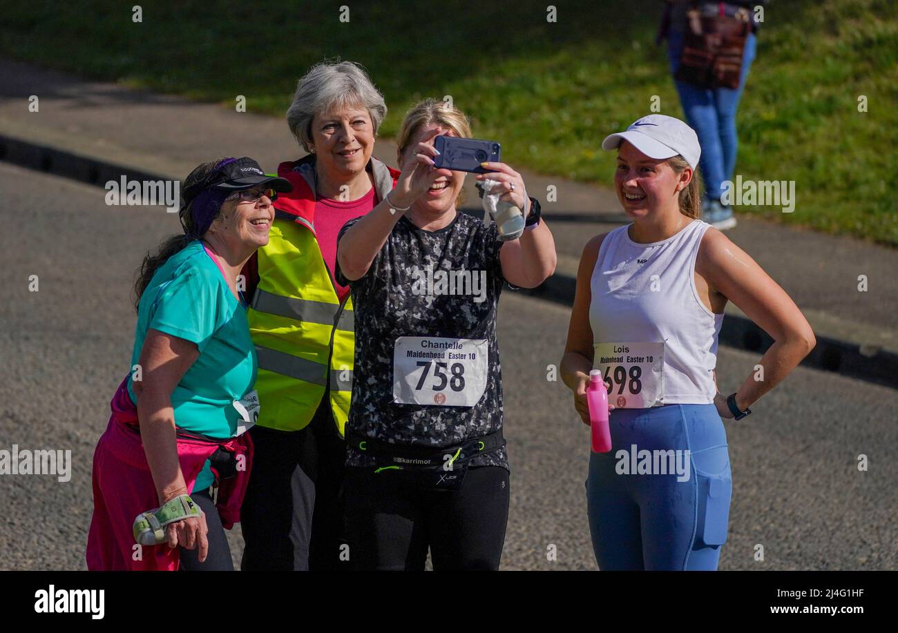 Former prime minister Theresa May poses for photographs with runners as ...