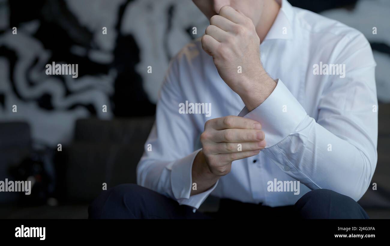 The man gets dressed and does his buttons on the sleeves of his white ...