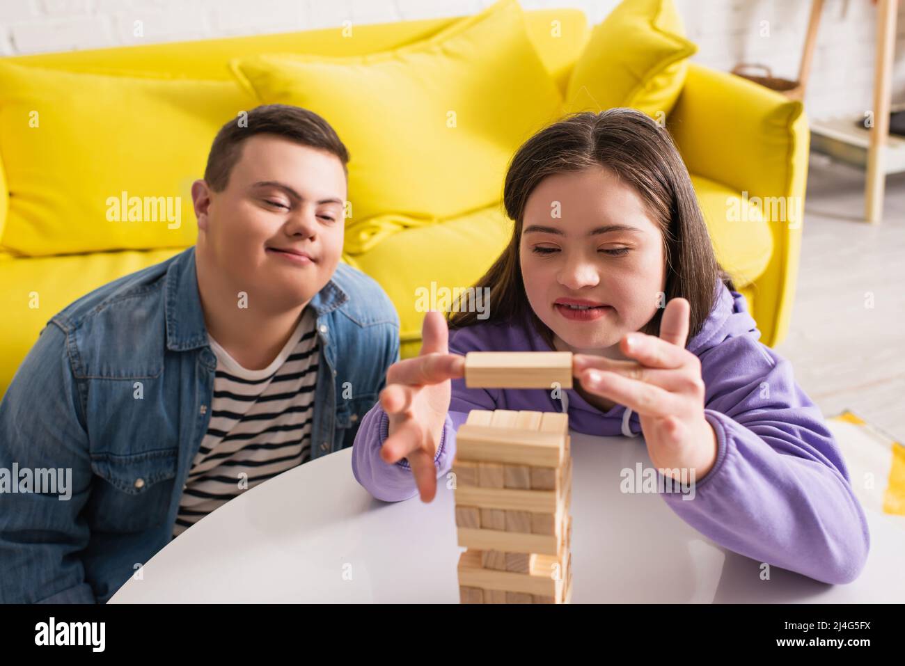 Positive teenagers with down syndrome playing wood blocks game at home ...