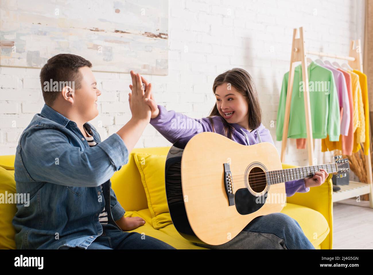 Positive teenagers with down syndrome giving high five near acoustic ...