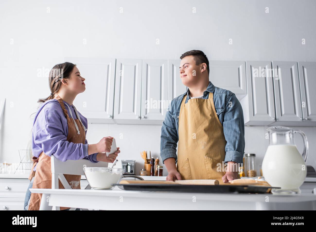 Positive couple with down syndrome cooking near food in kitchen Stock ...