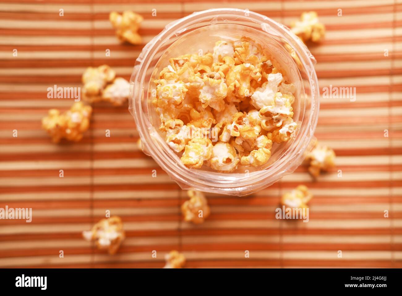 popcorn spilling from a plastic container on wooden background Stock ...