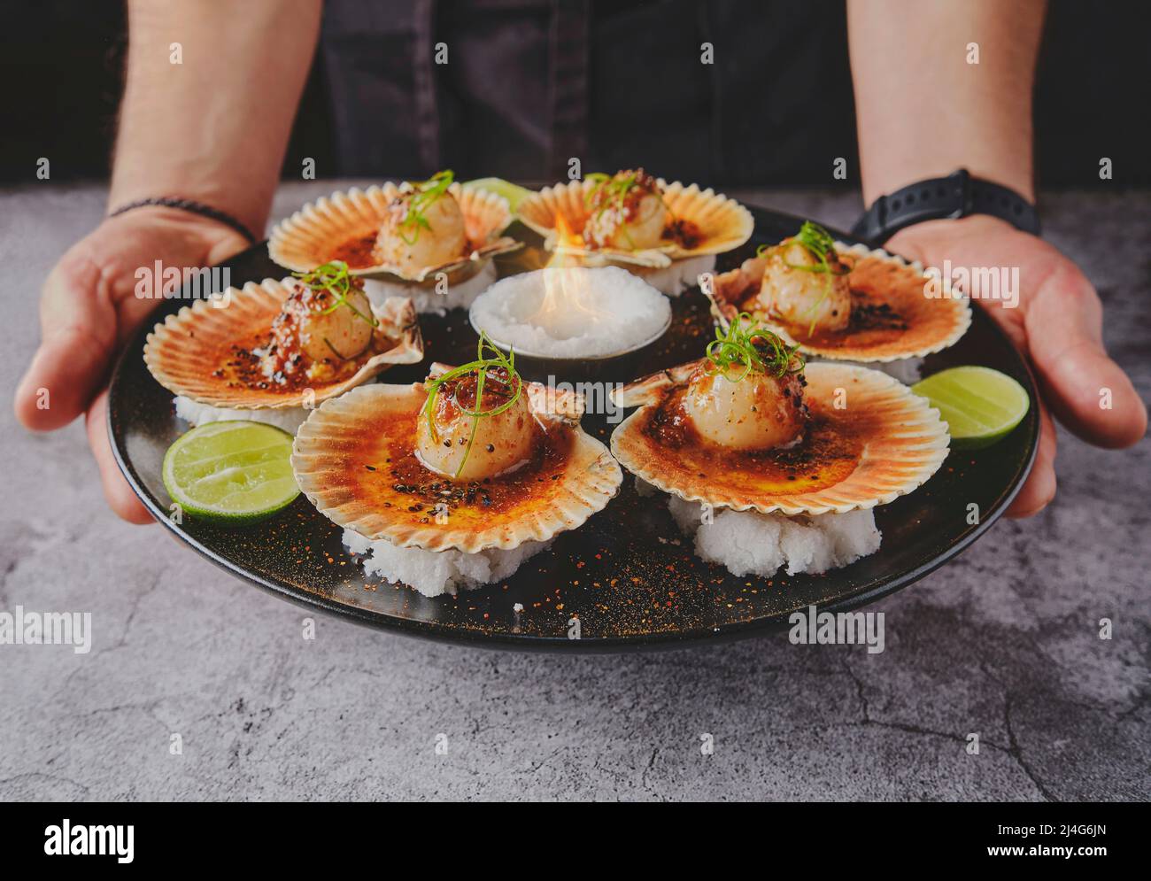 Scallops with flamed shells on a black plate. Luxury restaurant food ...