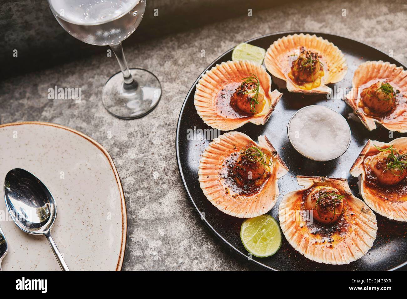 Scallops with flamed shells on a black plate. Luxury restaurant food ...