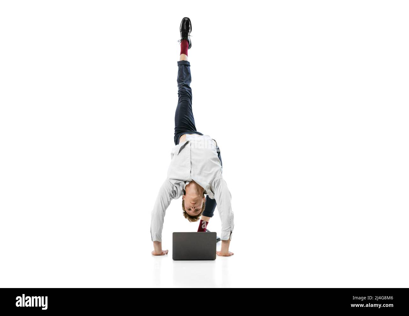 Creative Portrait Of Young Flexible Man Doing Backbend And Typing On