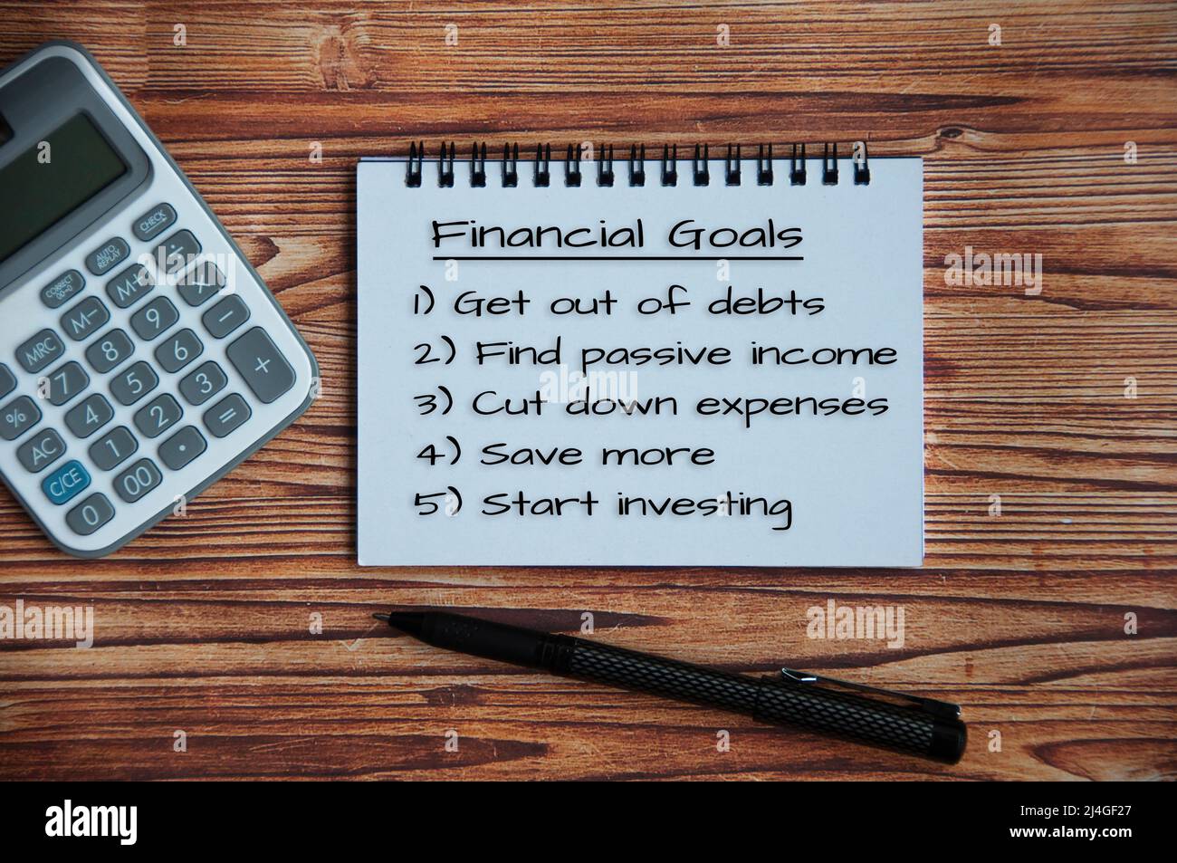 Financial goals text on notepad with calculator and pen on a wooden ...