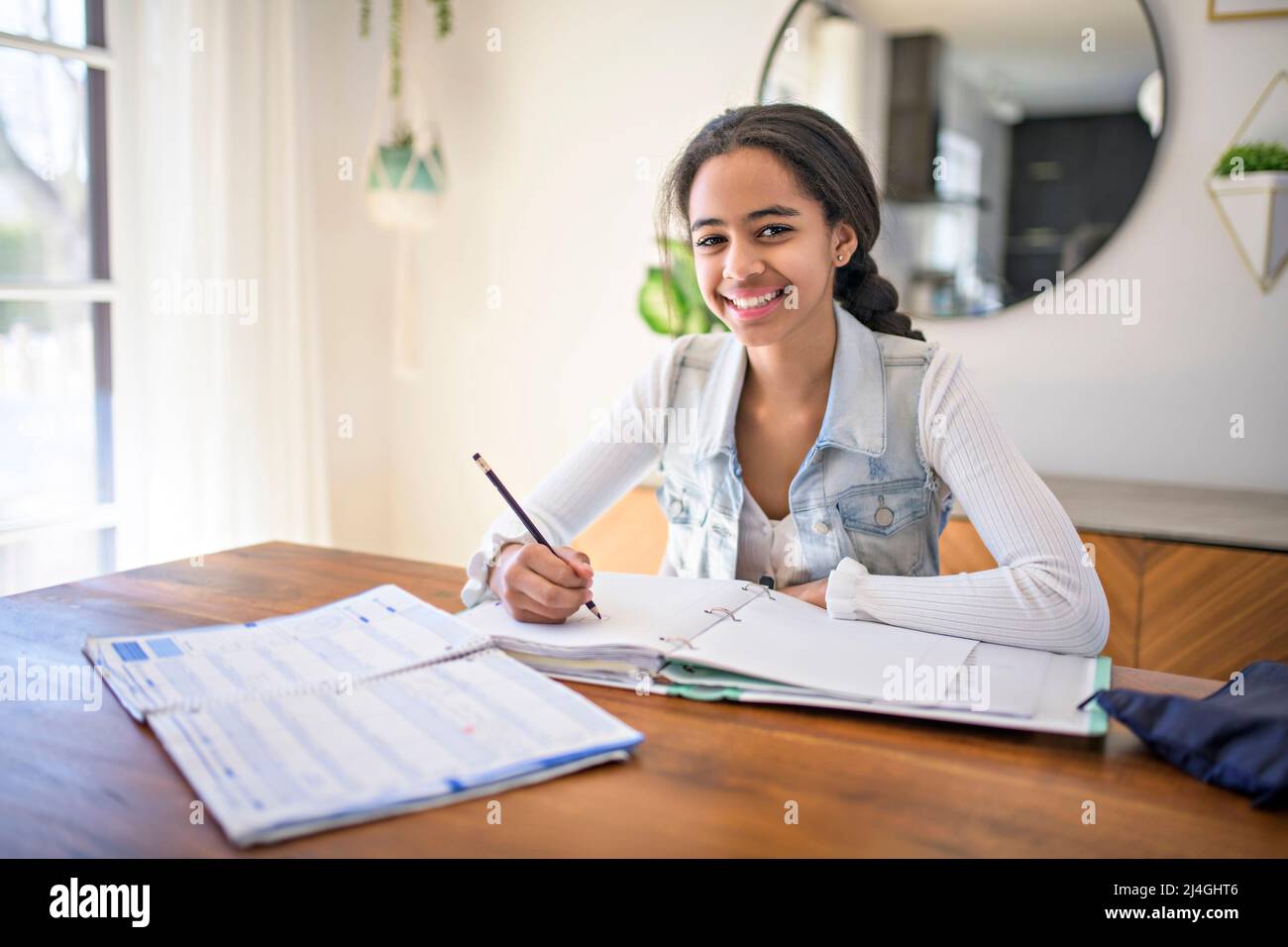 African American teen girl learning school tasks at home, writing notes ...