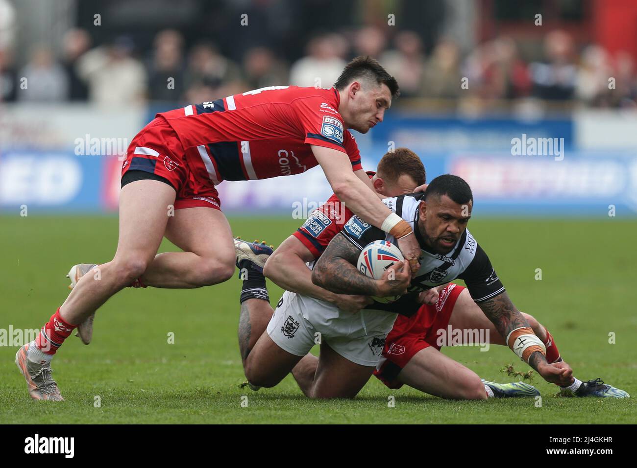Manu Ma'u #12 of Hull FC is stopped by Frankie Halton #27 and Sam Wood ...