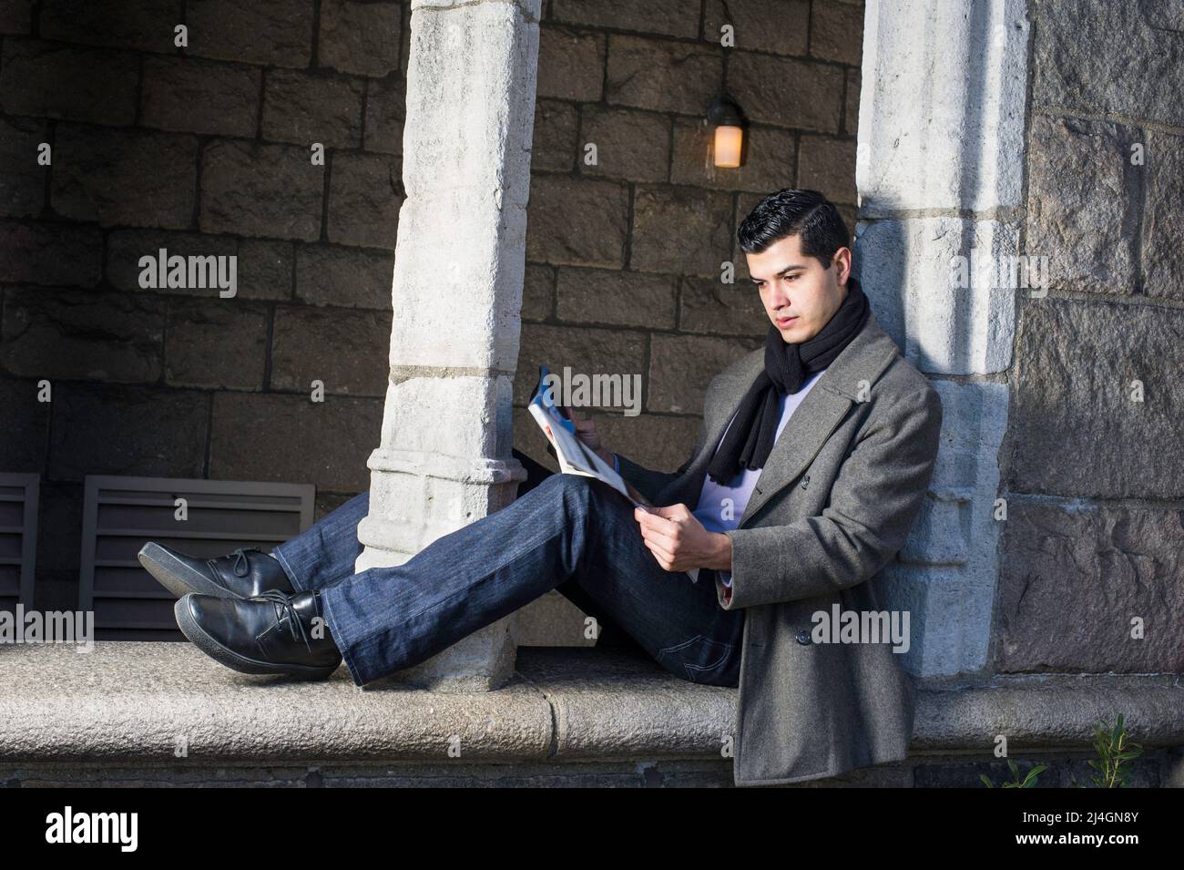 A young guy is sitting on a old window frame and reading Stock Photo ...