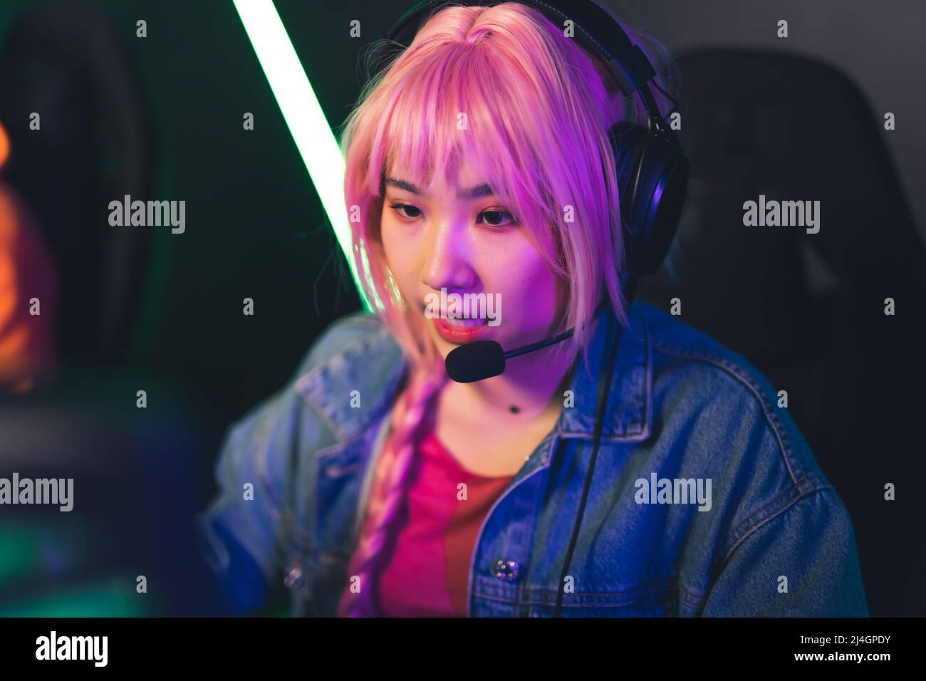 Excited and smiling gamer girl in headset with a mic playing an online ...