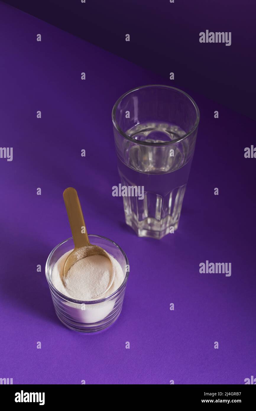 Glass with collagen dissolved in water and collagen protein powder on ...