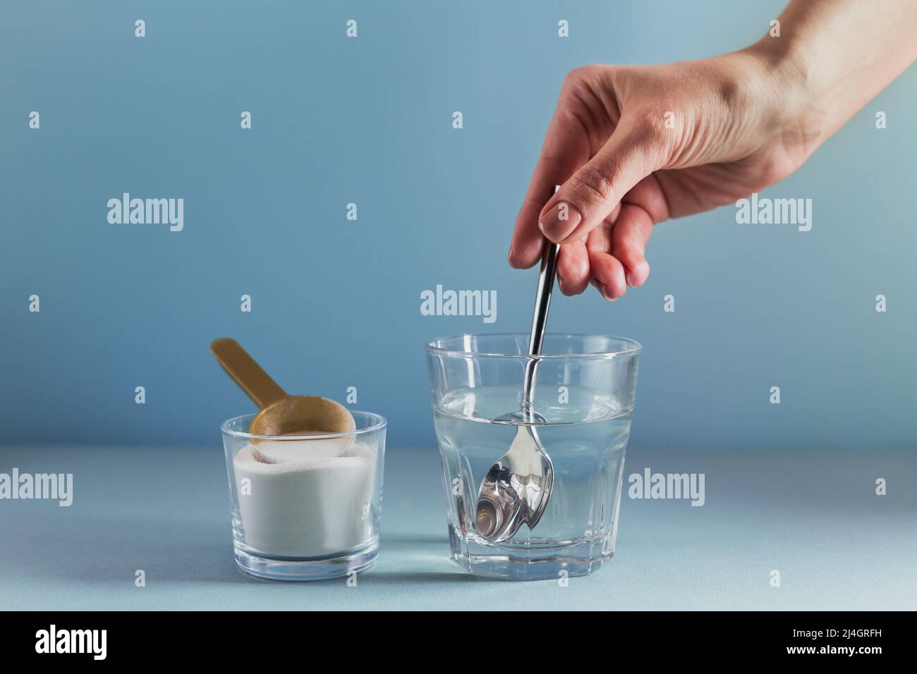 Glass with collagen dissolved in water and collagen protein powder on ...